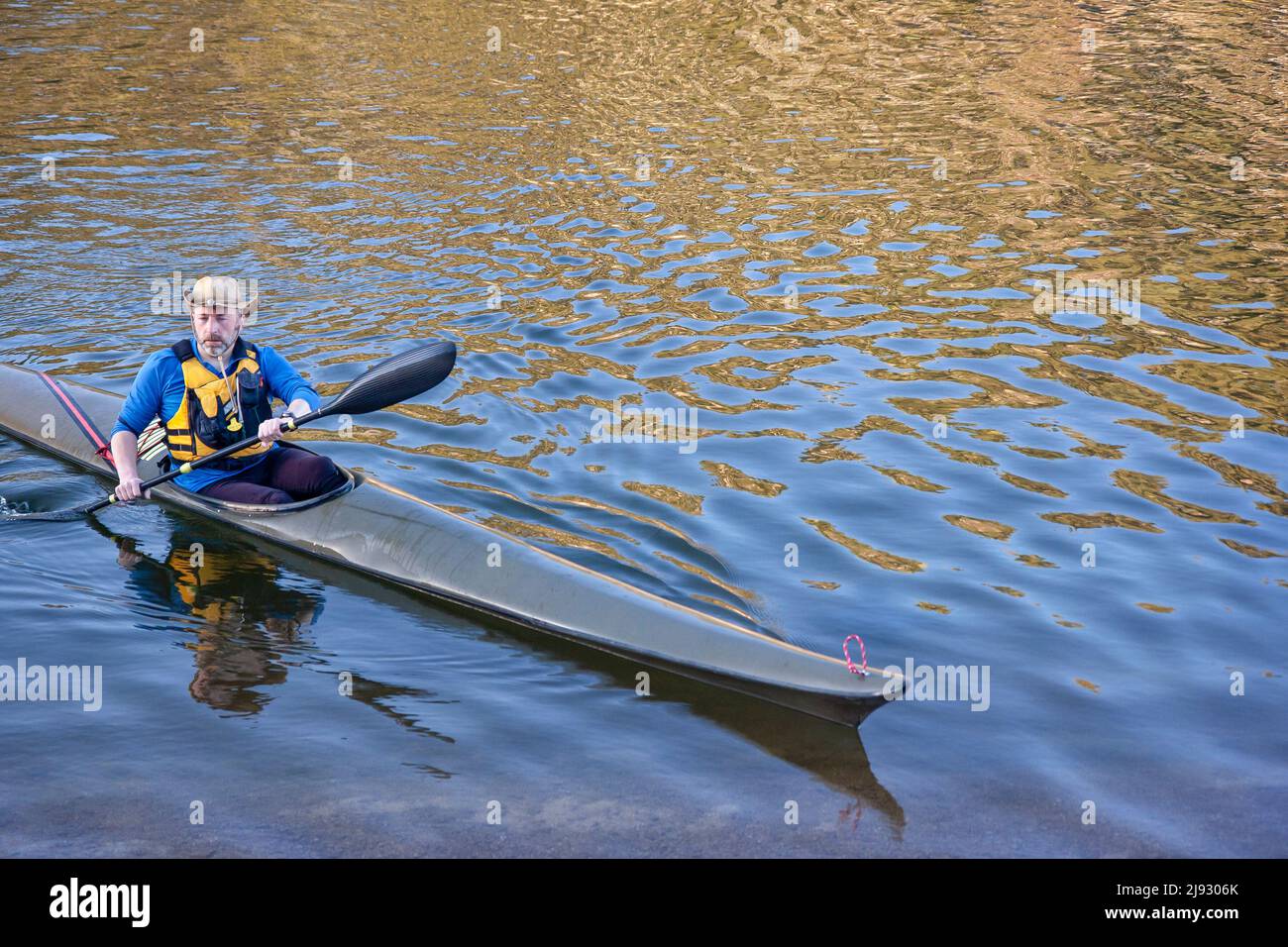 mature male paddler in a long and narrow racing sea kayak with a wing ...