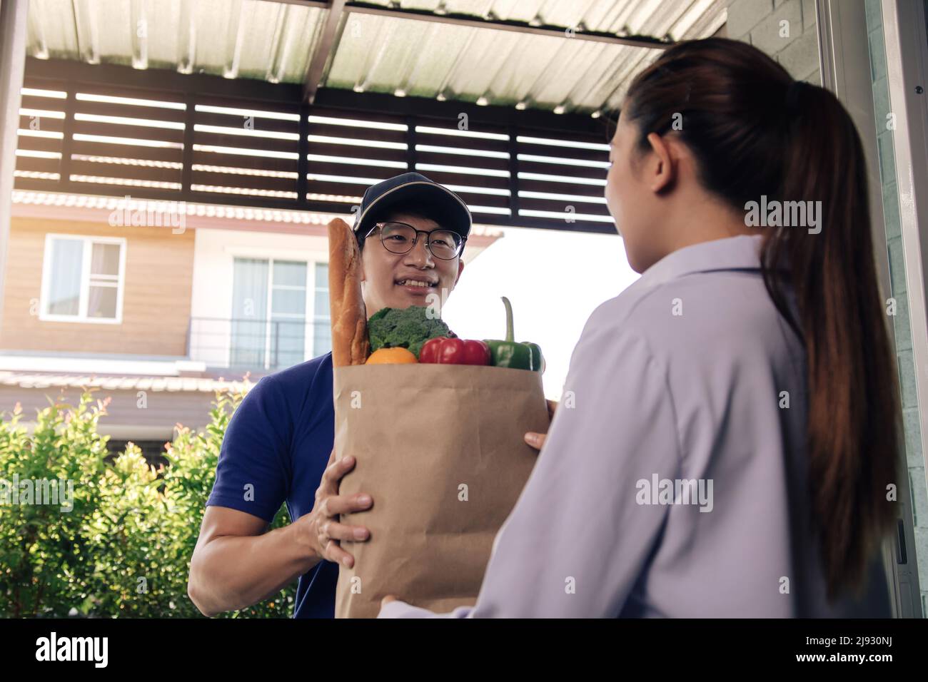 Delivery of an asian man handling a bag of food to a female customer at ...
