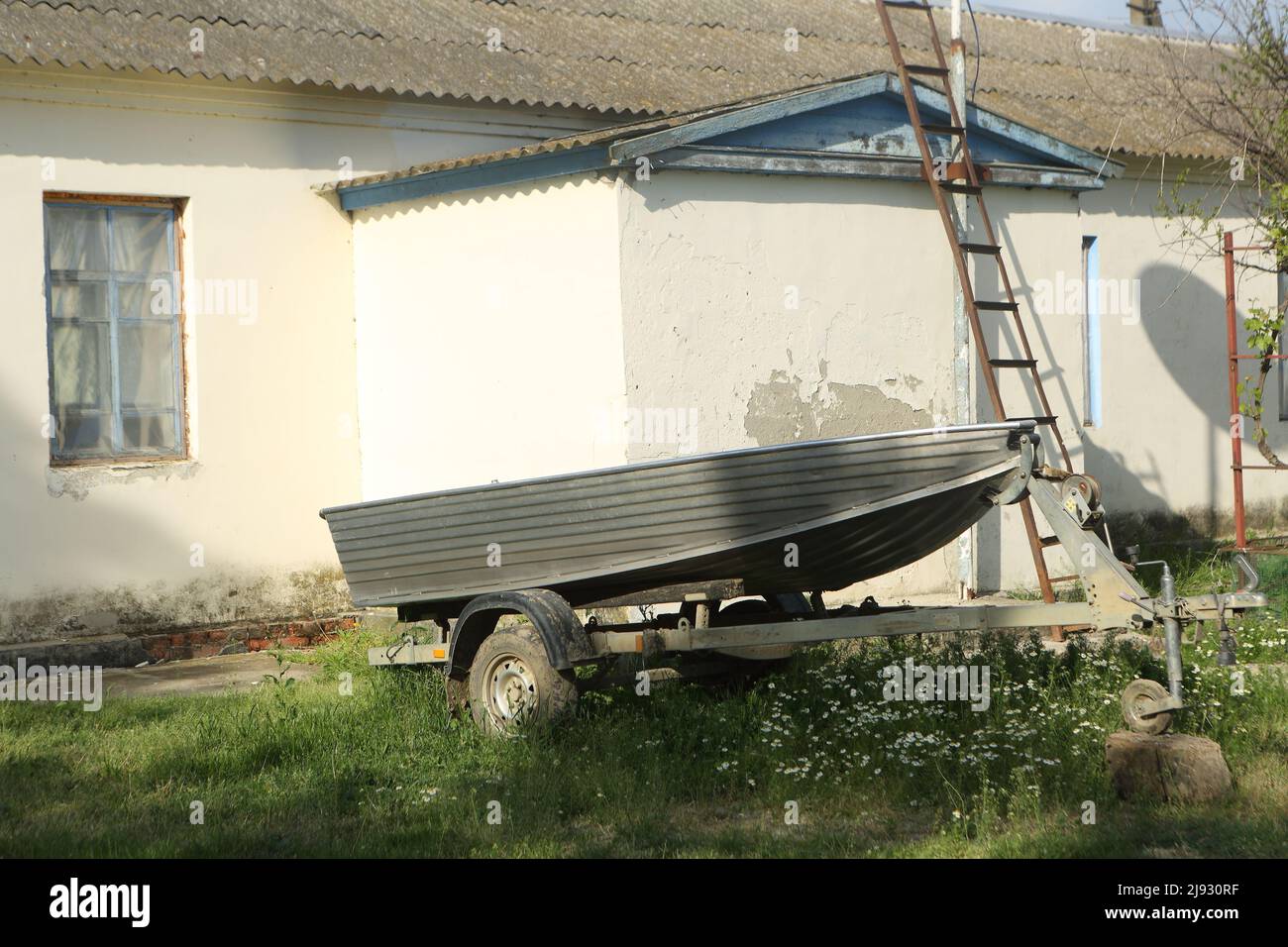 Metal boat on wheels near the house Stock Photo - Alamy