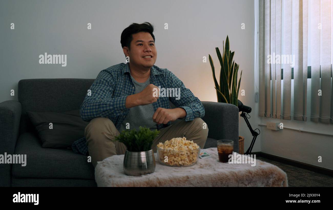 Asian men sit and win their favorite teams broadcasting live football ...