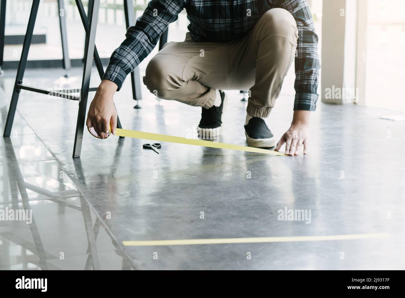 Male workers preparing masking tape to symbolize social distances Stock ...