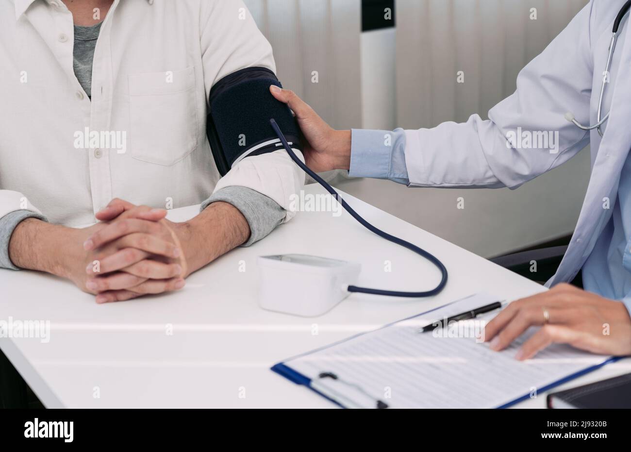 Asian doctor is using a patient's blood pressure monitor at the time of ...