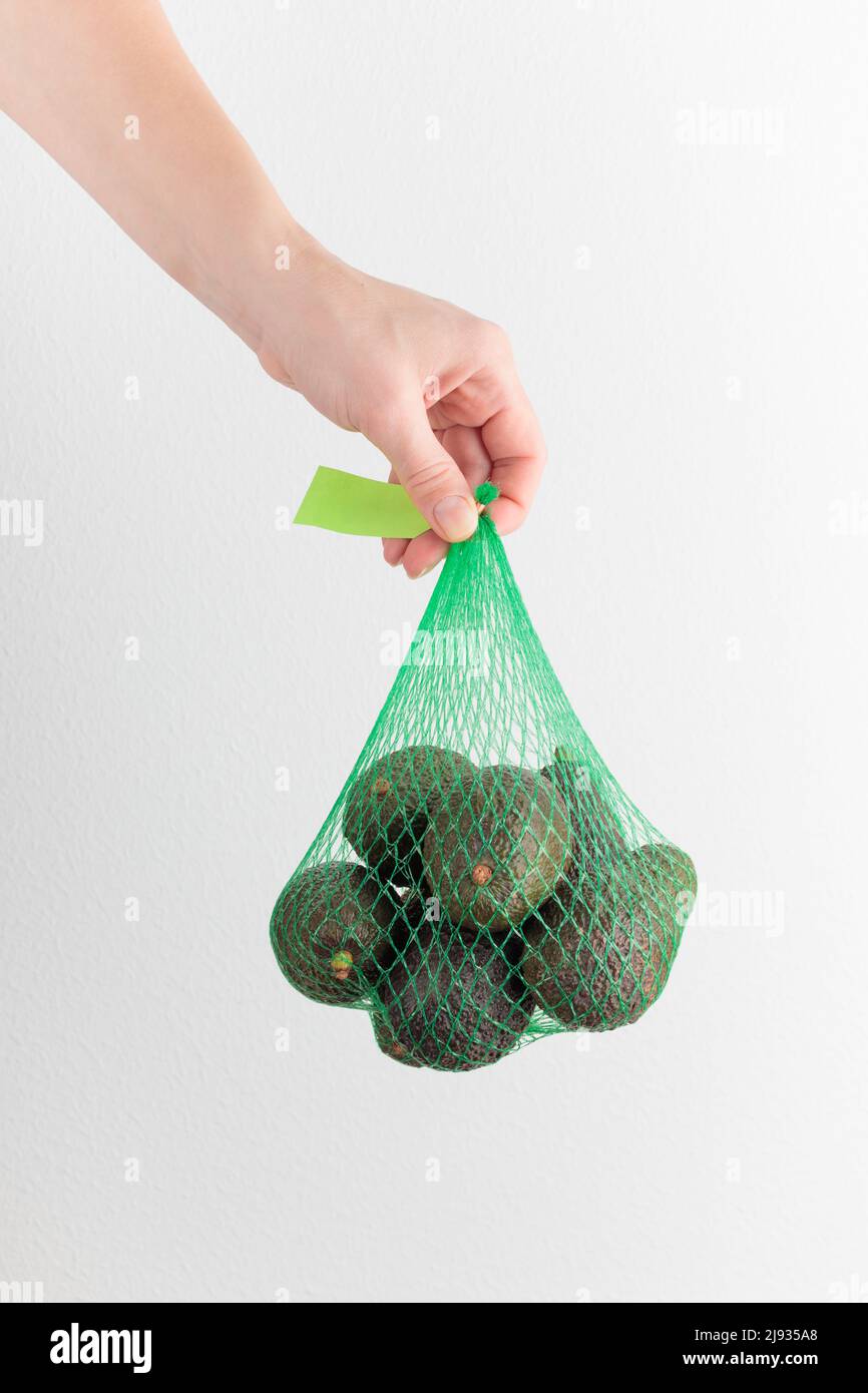 Hand holding an avocado bag on a white background Stock Photo - Alamy