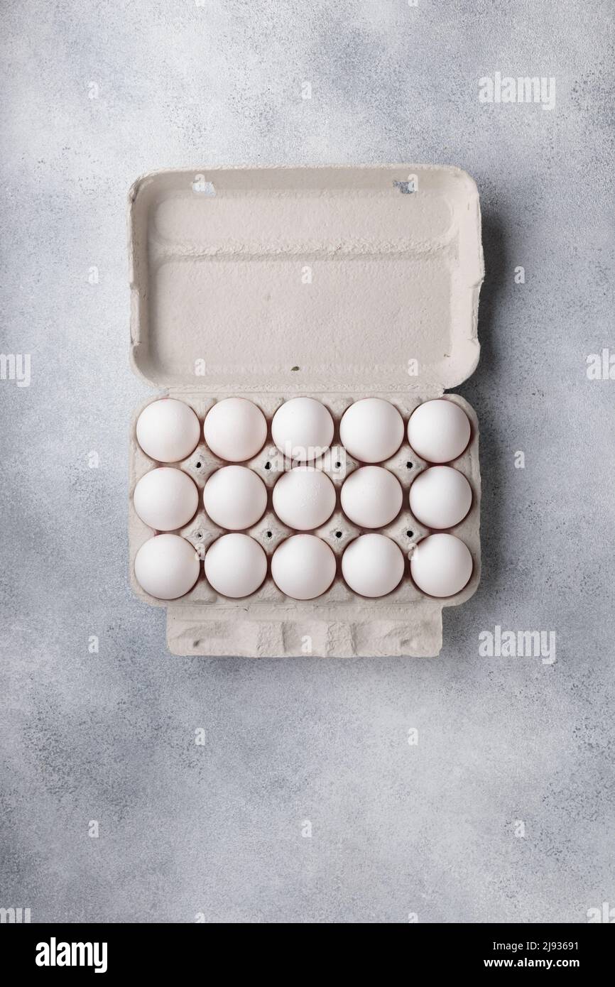White eggs in a large paper container box top view on a neutral ...