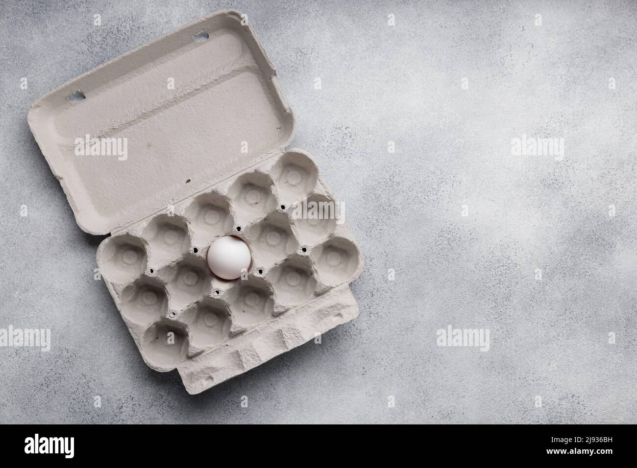 White eggs in a large paper container box top view on a neutral ...