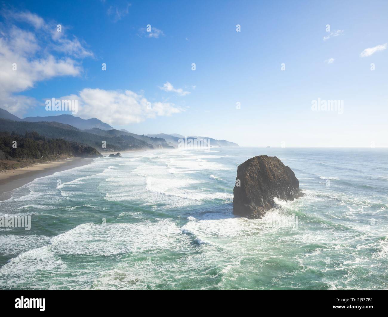 Big stone in the sea, ocean. The sandy shore and mountains are visible ...
