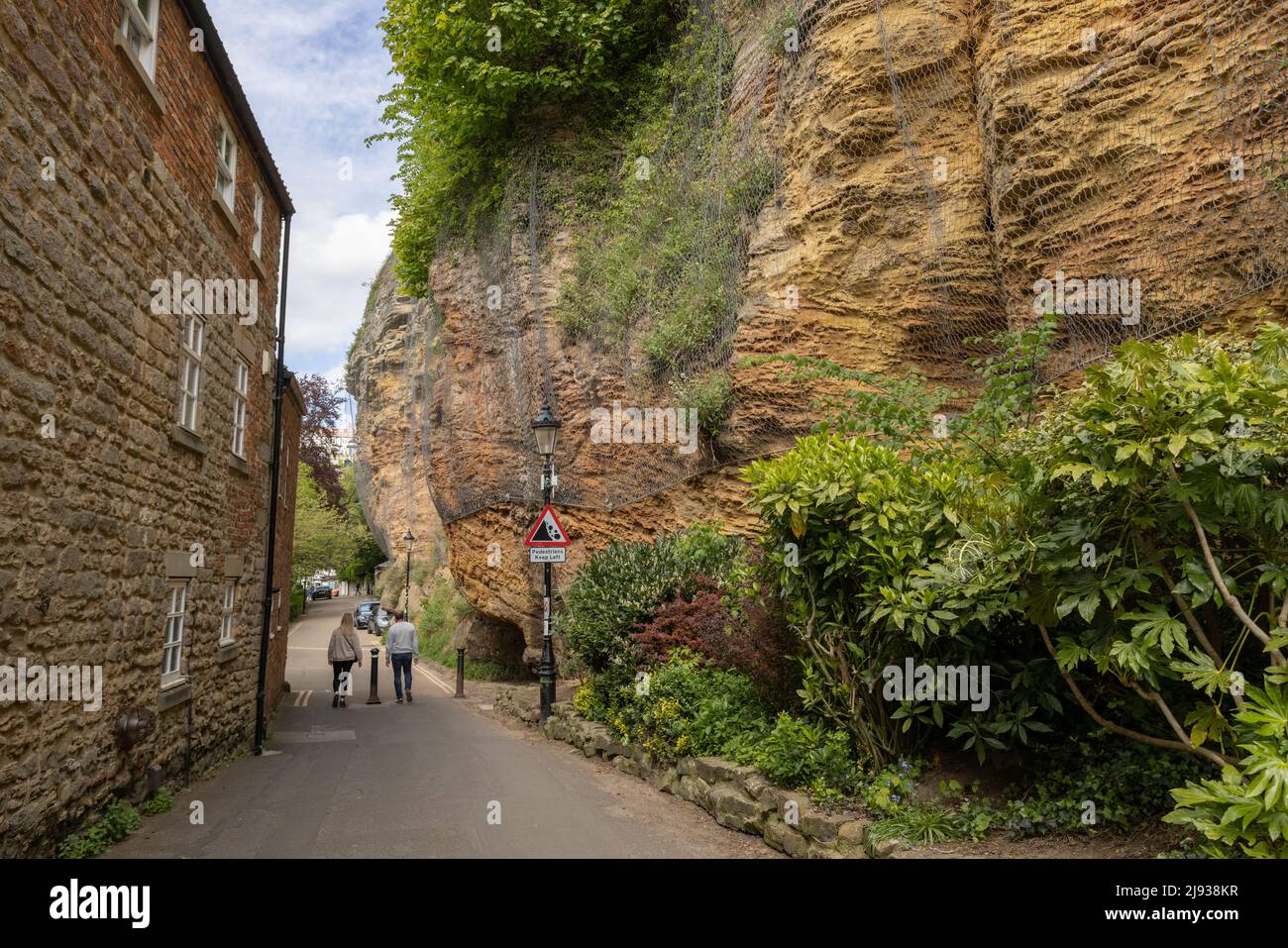 People walking near falling rocks sign and security metal net covering ...