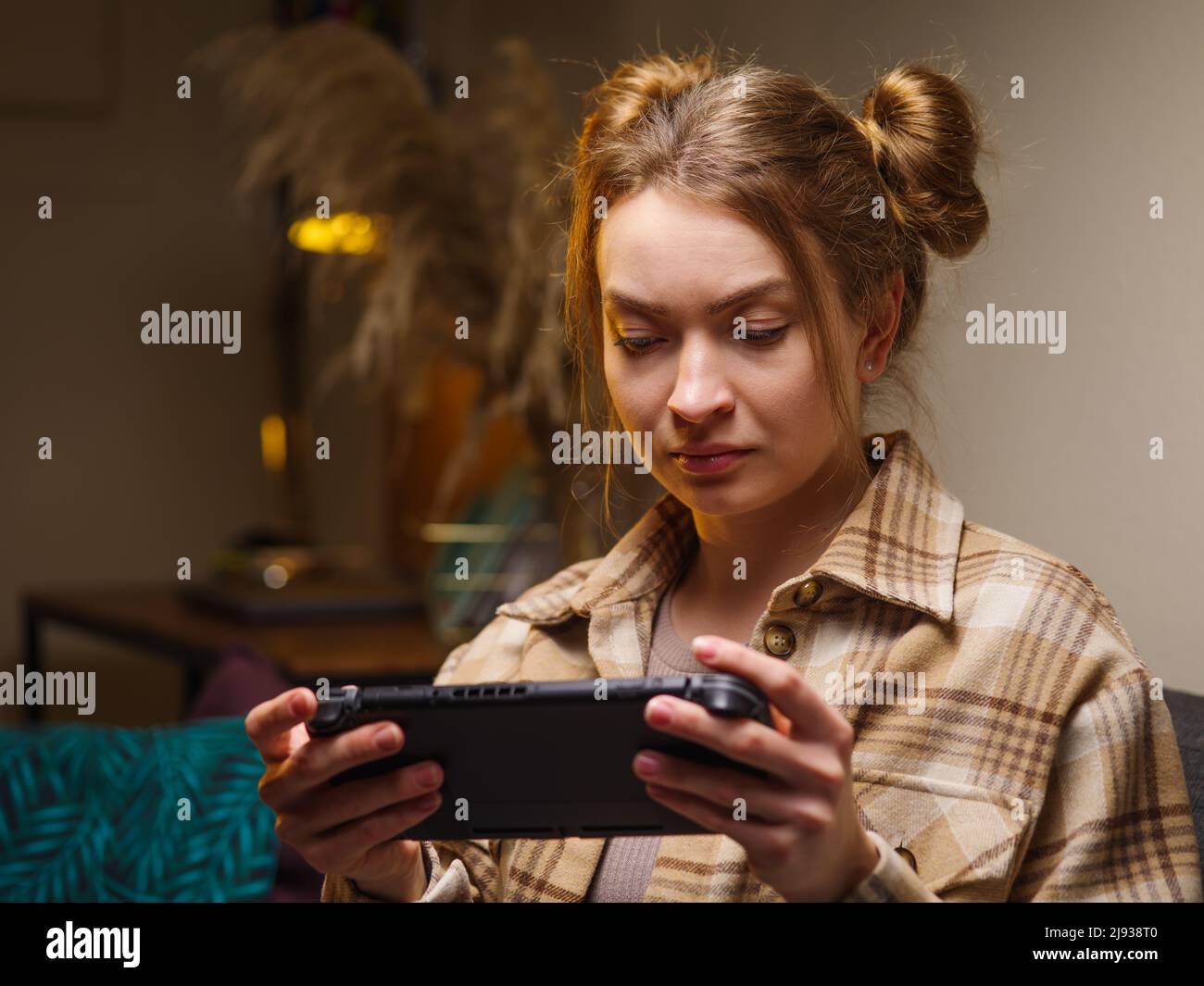 Girl gamer looks thoughtfully at the screen of a portable game console ...