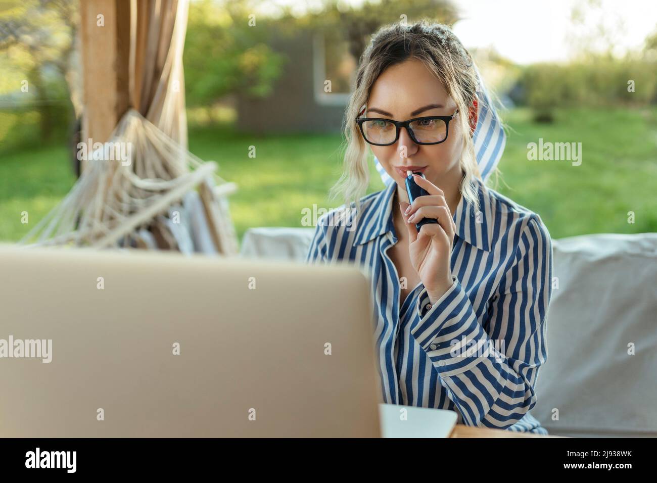 freelance girl works at a computer and smokes an electrode cigarette ...