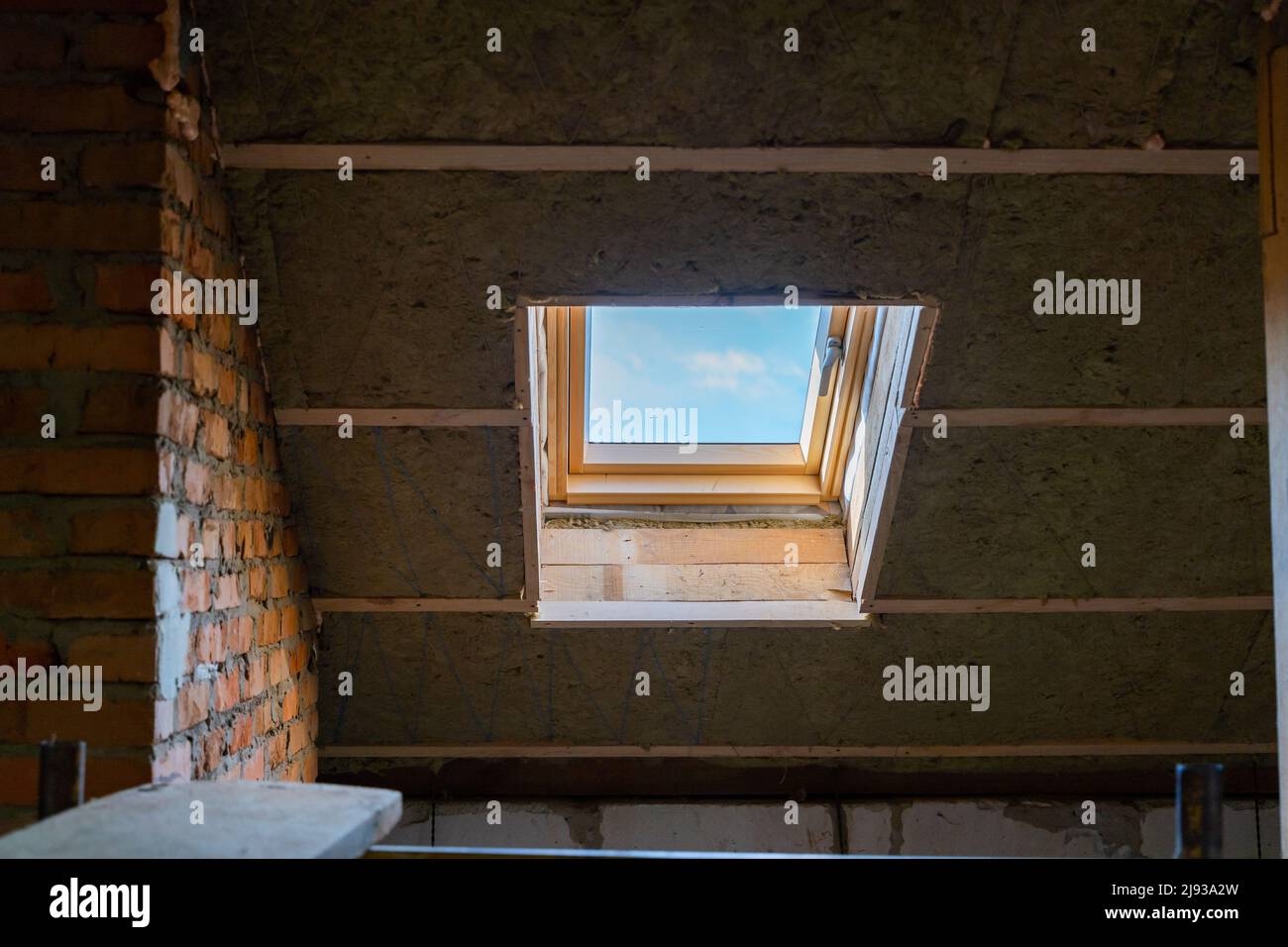 A window overlooking the blue sky built into a roof insulated with ...
