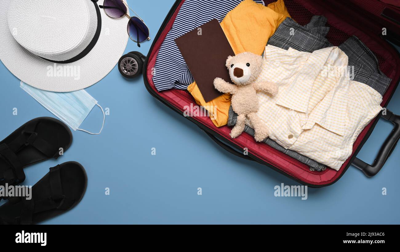 Top view open suitcase with casual clothes and passports over blue ...