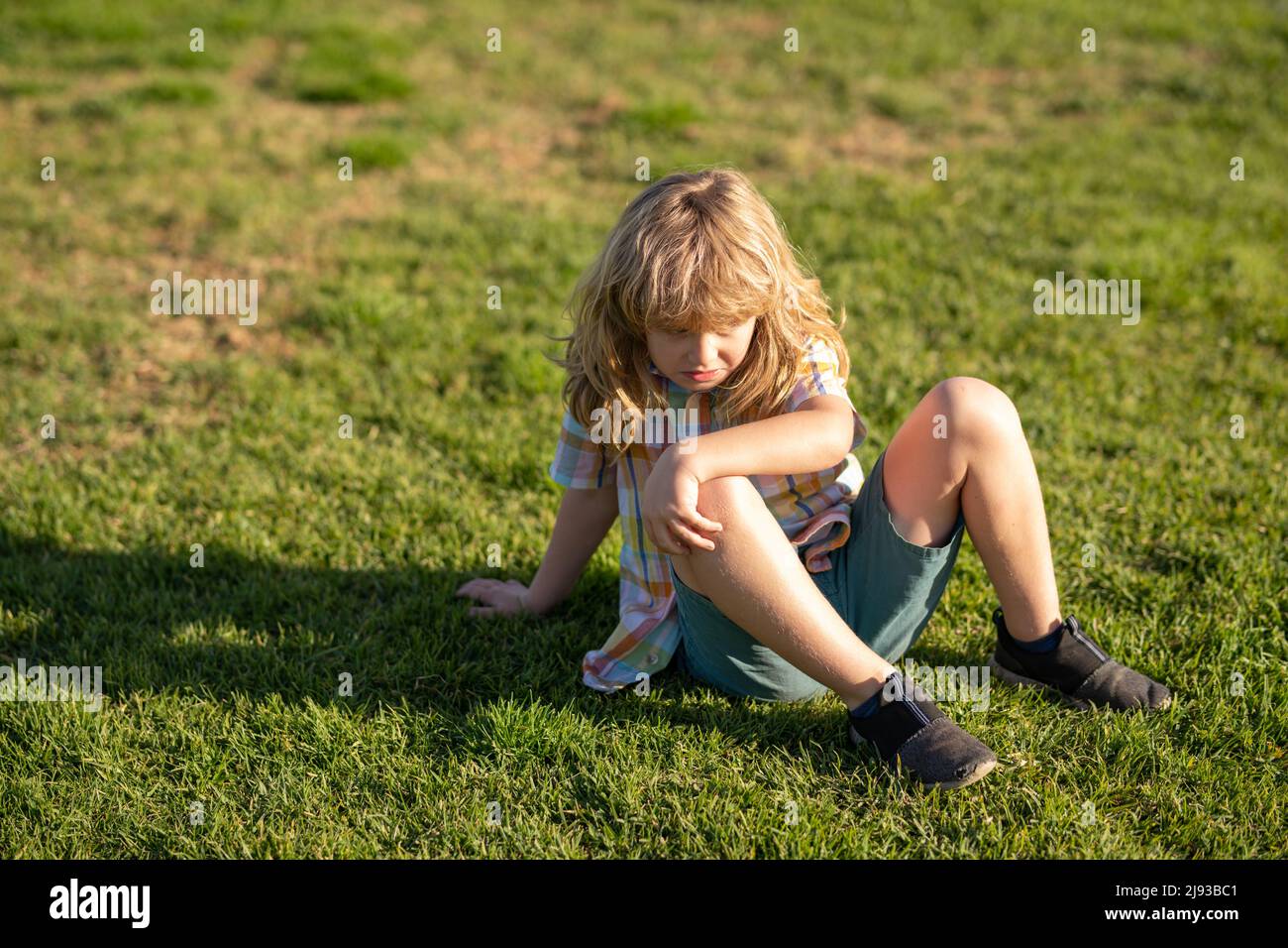 A boy fell on a walk in the park, a broken knee Child in park outdoor ...