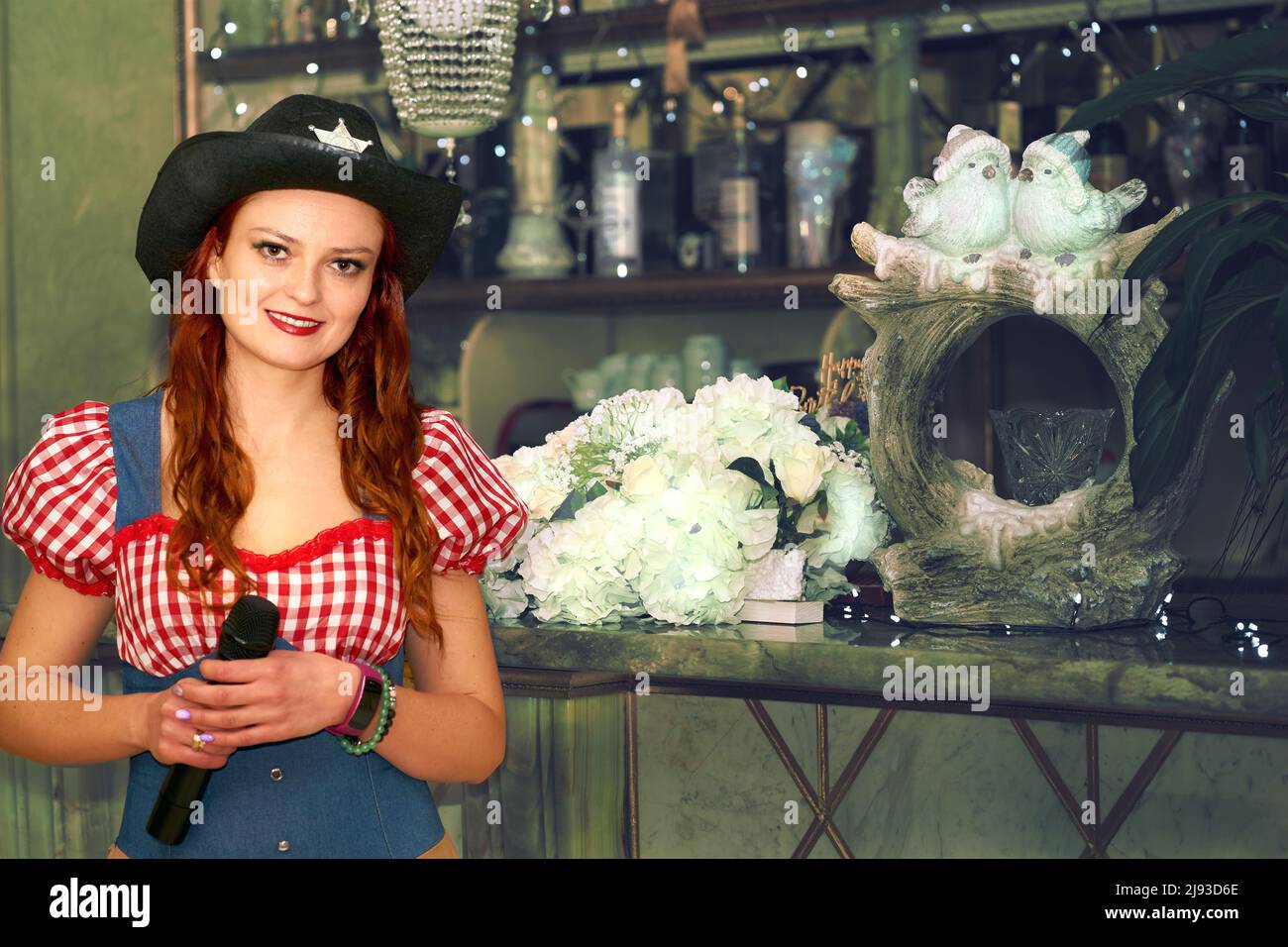 Young pretty woman leading a party, holiday, karaoke, wedding in cowboy ...