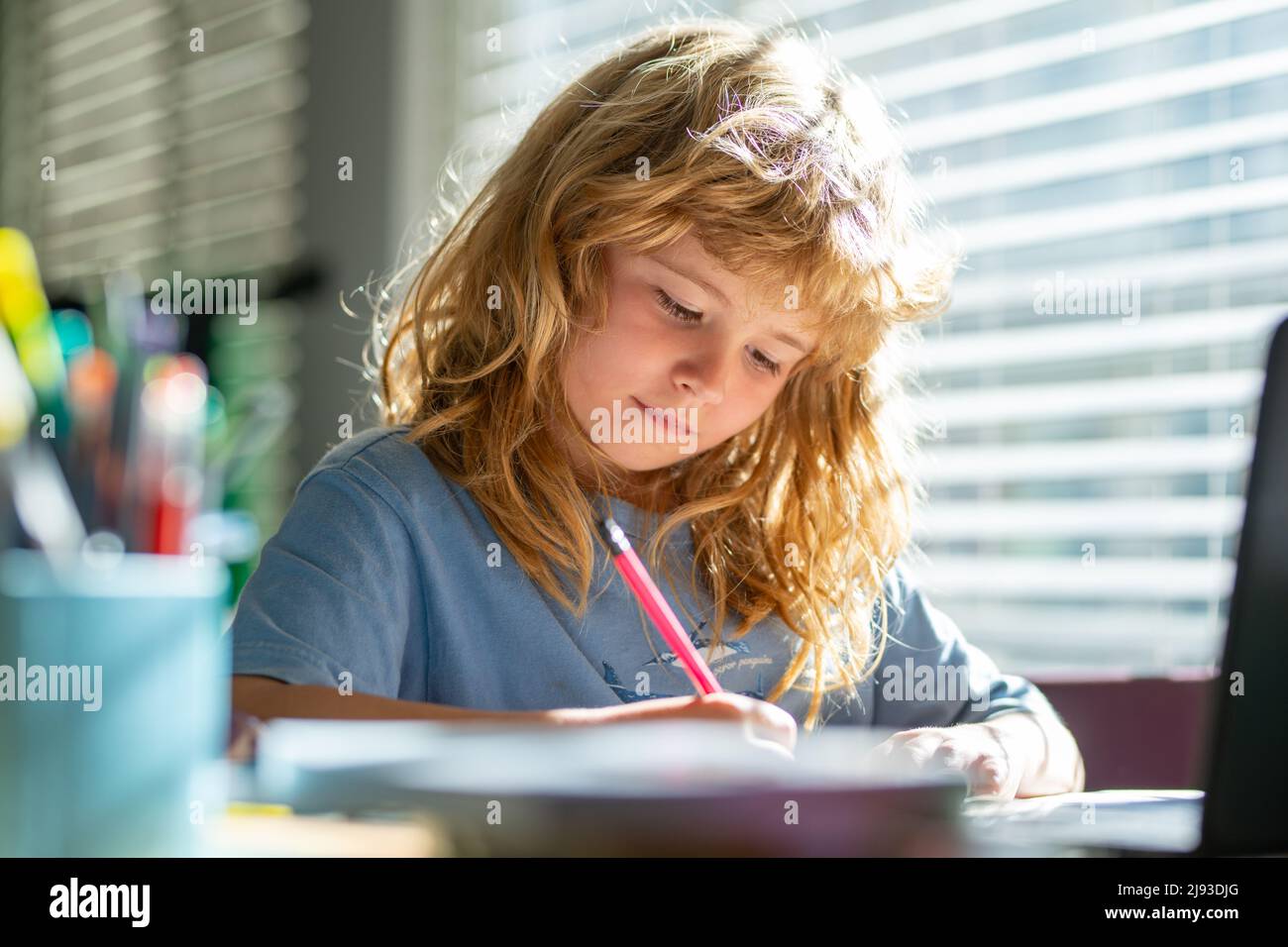 Portrait school kid siting on table doing homework. Concentrated ...