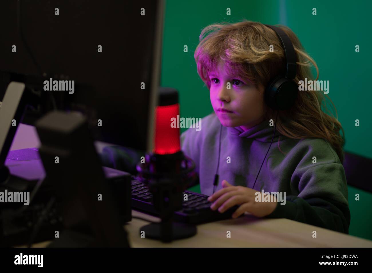 Kid using pc at night. Child with computer in a dark room. A little boy ...