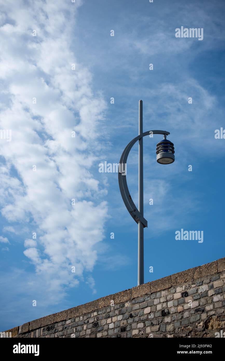 Modern curved lamp post rises up against a cloudy blue sky Stock Photo ...