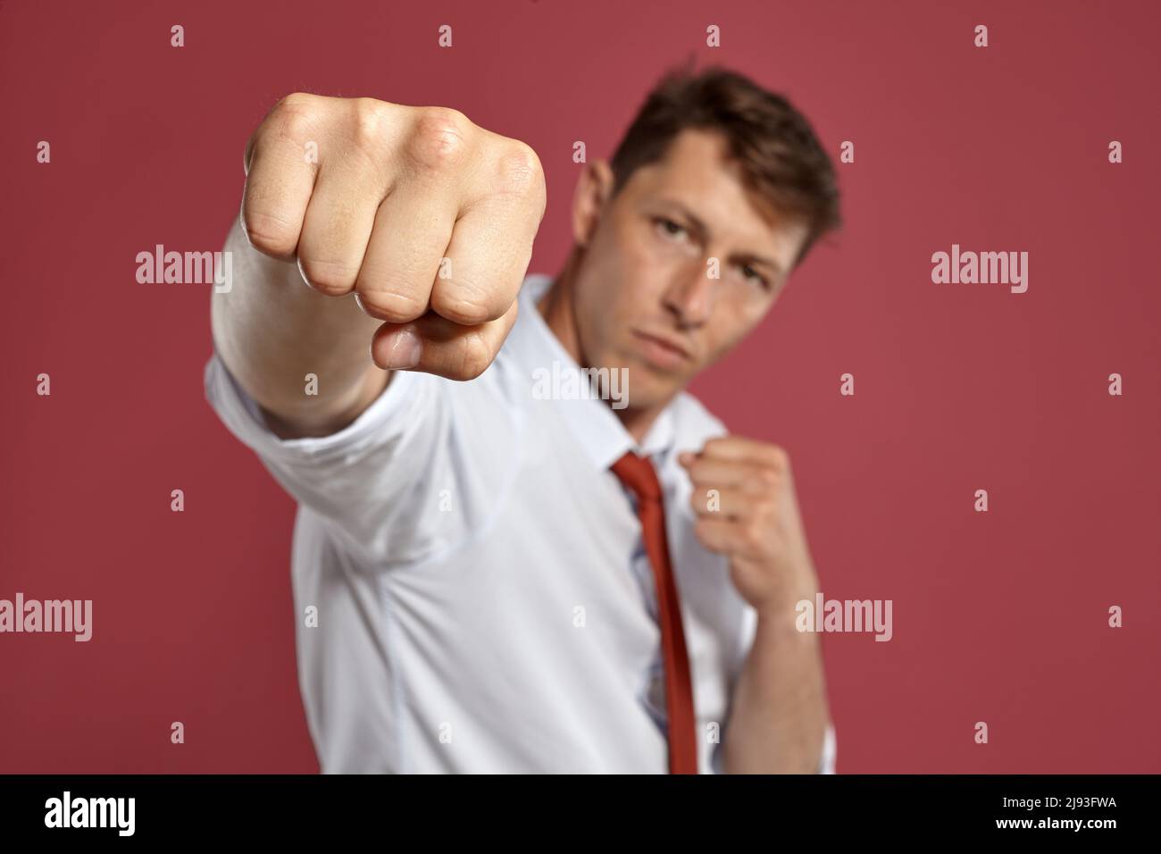 Portrait of a young brunet man posing in a studio against a red ...