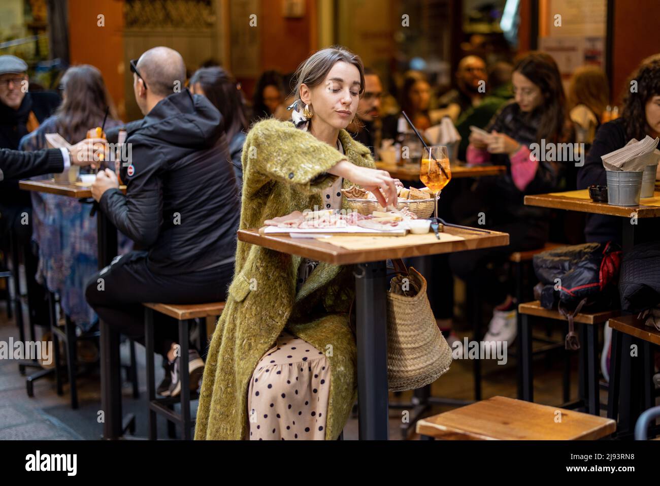 Woman sitting on crowded street at bar or restaurant outdoors Stock ...