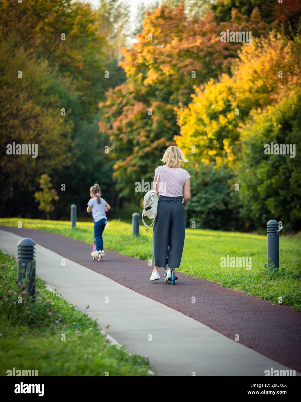 Mom rides a scooter with children in the park in summer Stock Photo - Alamy
