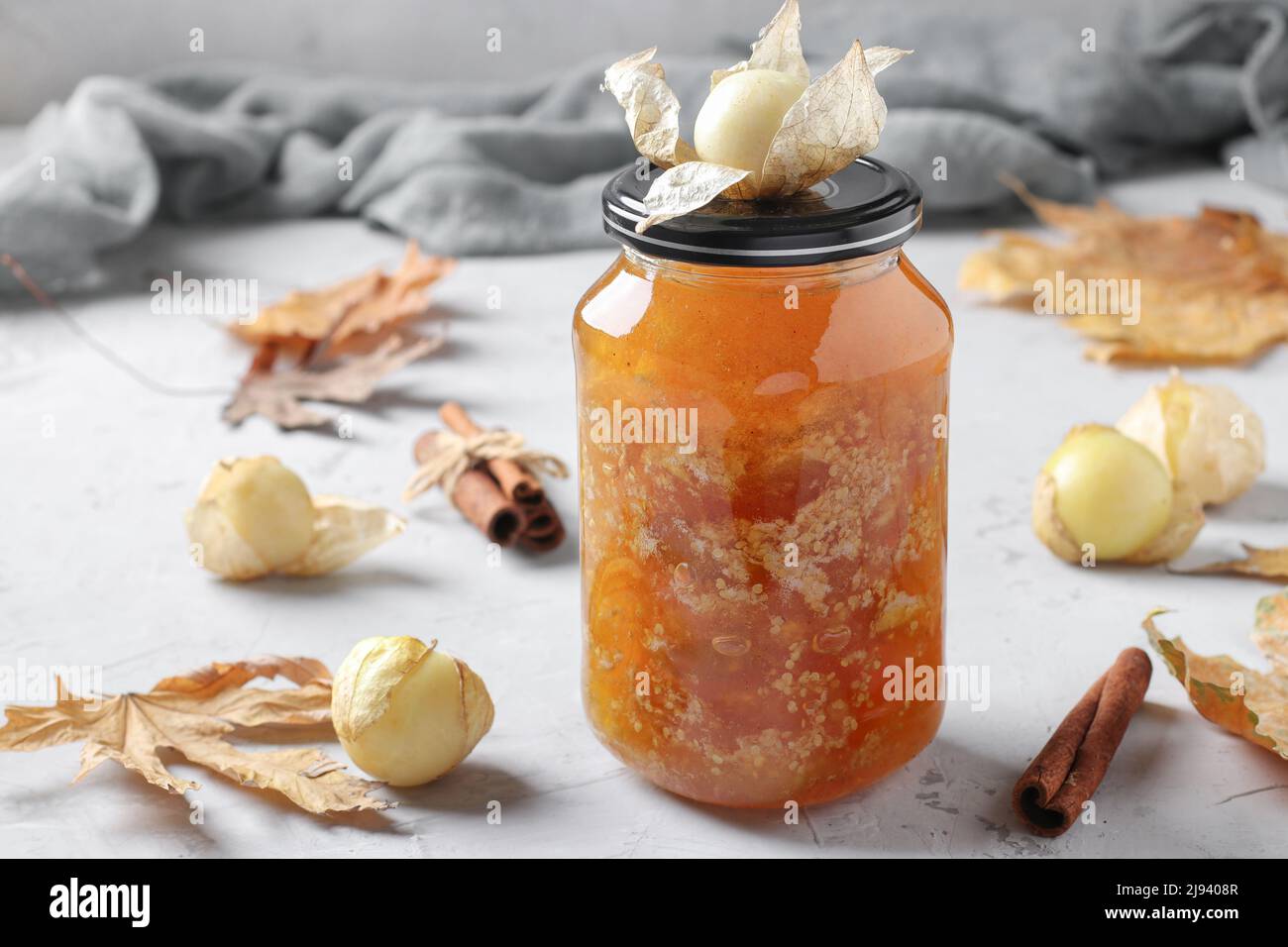 Homemade transparent physalis jam with cinnamon in glass jar on gray ...