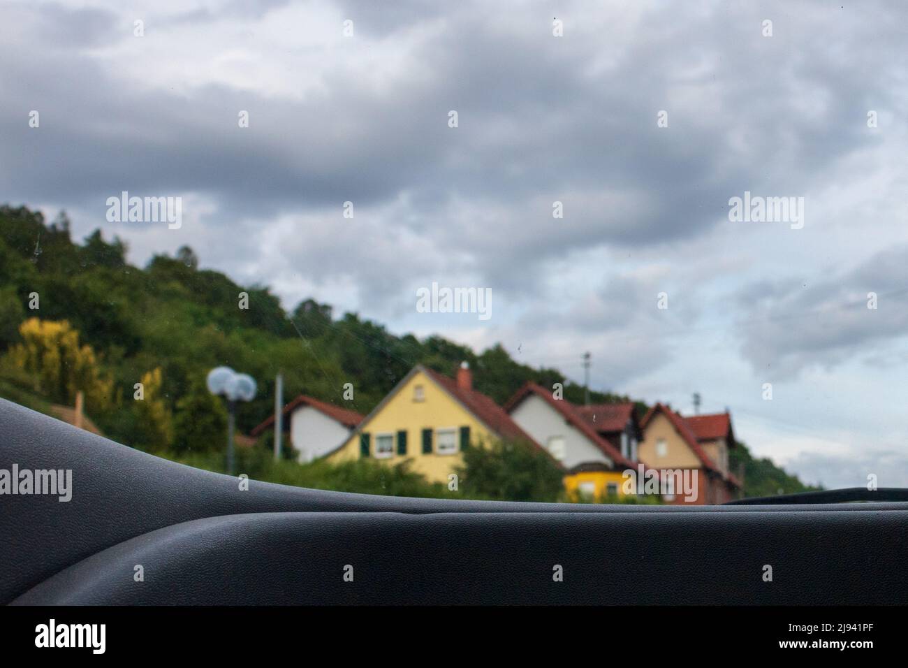 Car window view with car dashboard with blurred houses and sky in rural ...