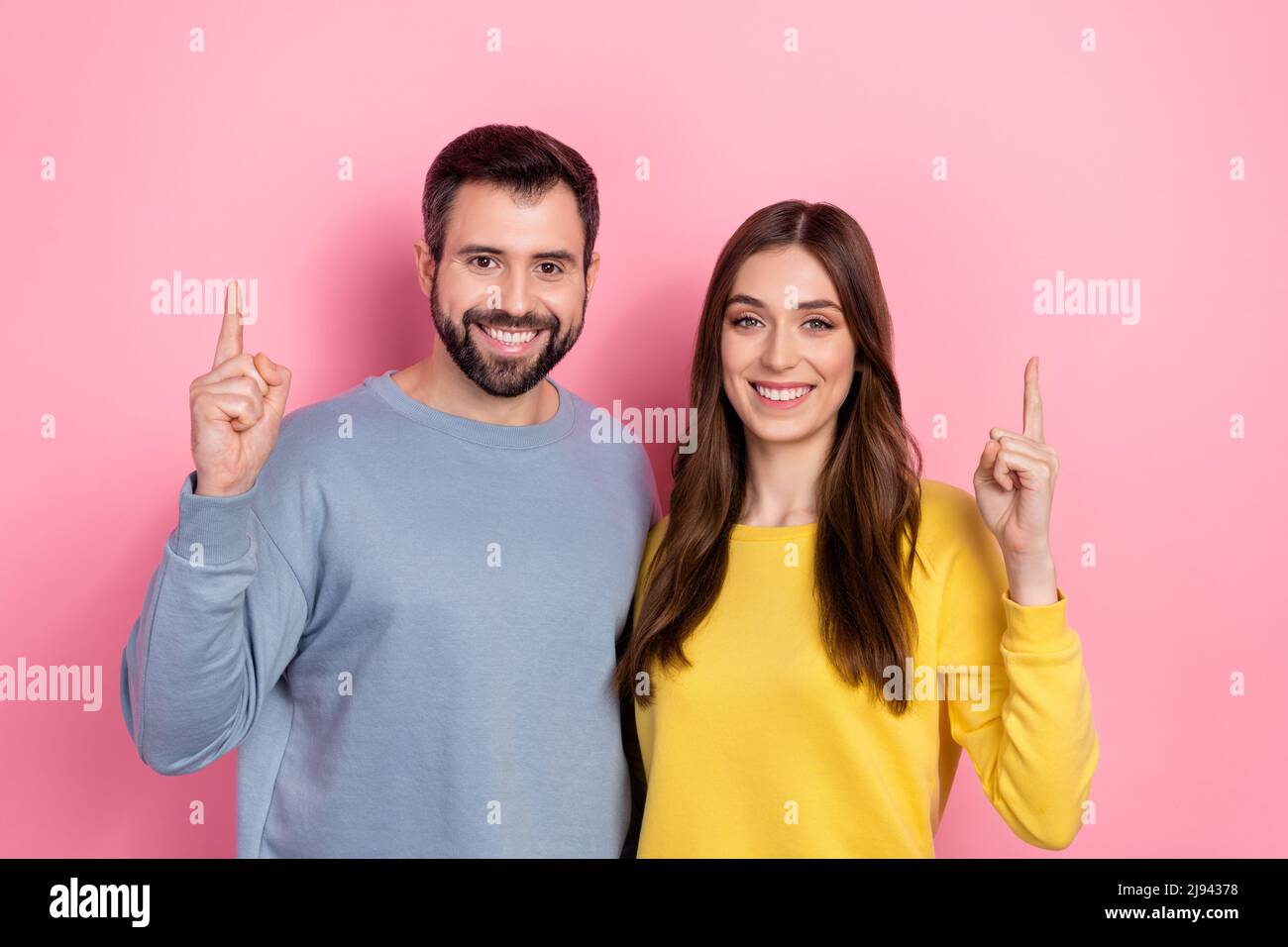 Portrait of two positive friendly partners indicate finger up empty ...