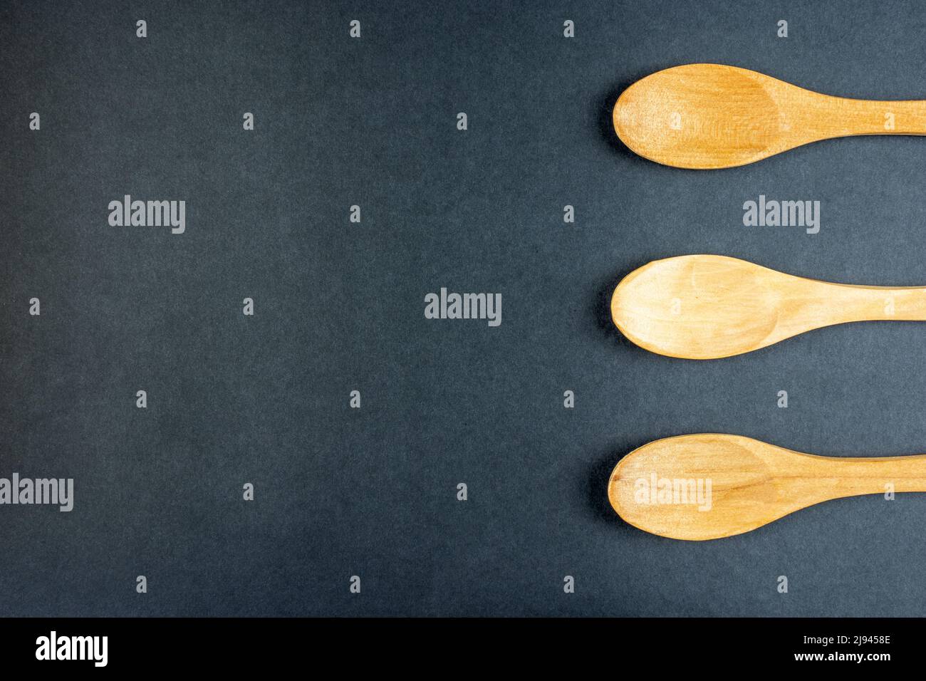 Wooden spoons small made of light brown wood on dark background with ...