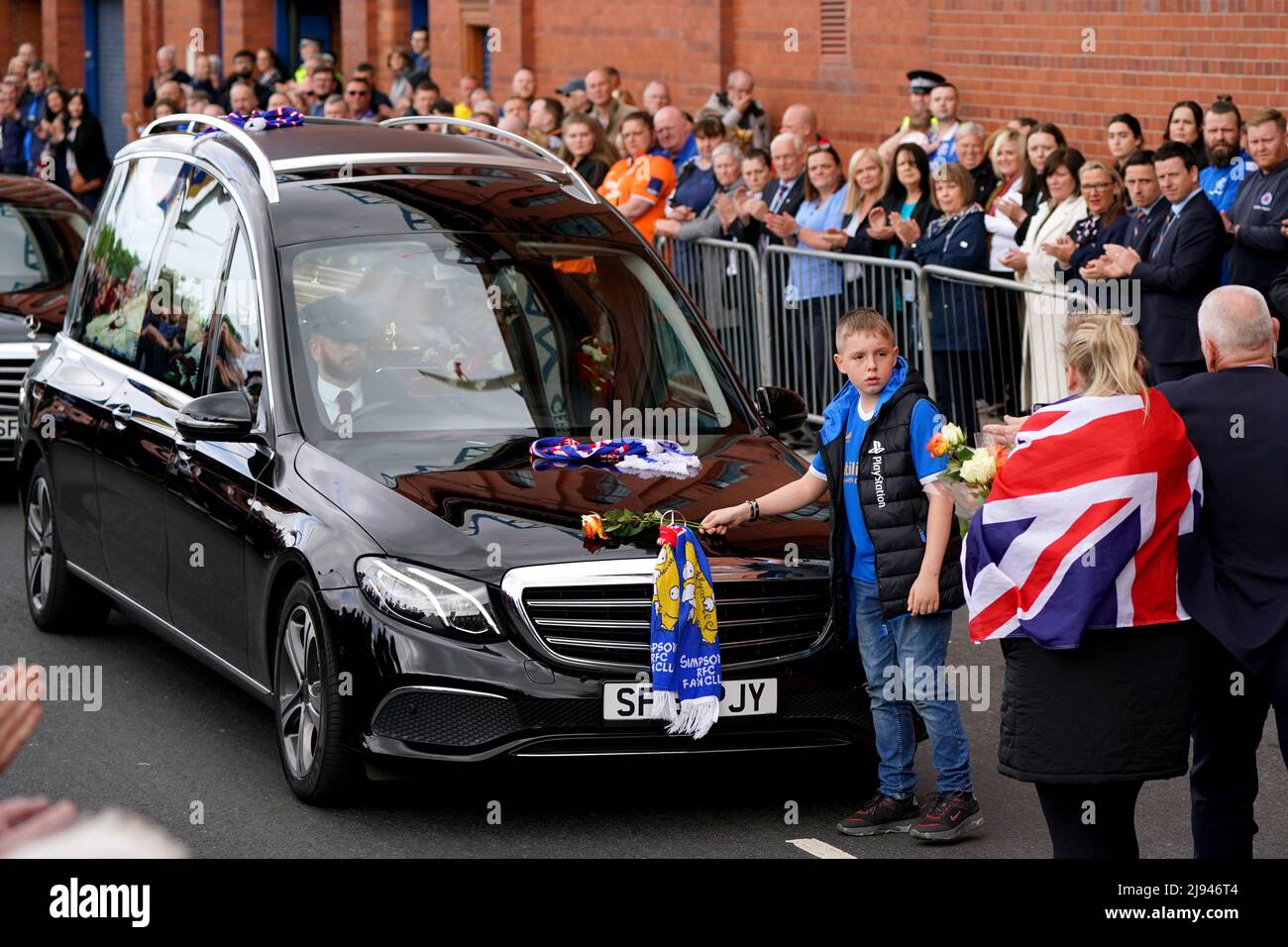A young Rangers fan places a rose on the hearse as the funeral ...