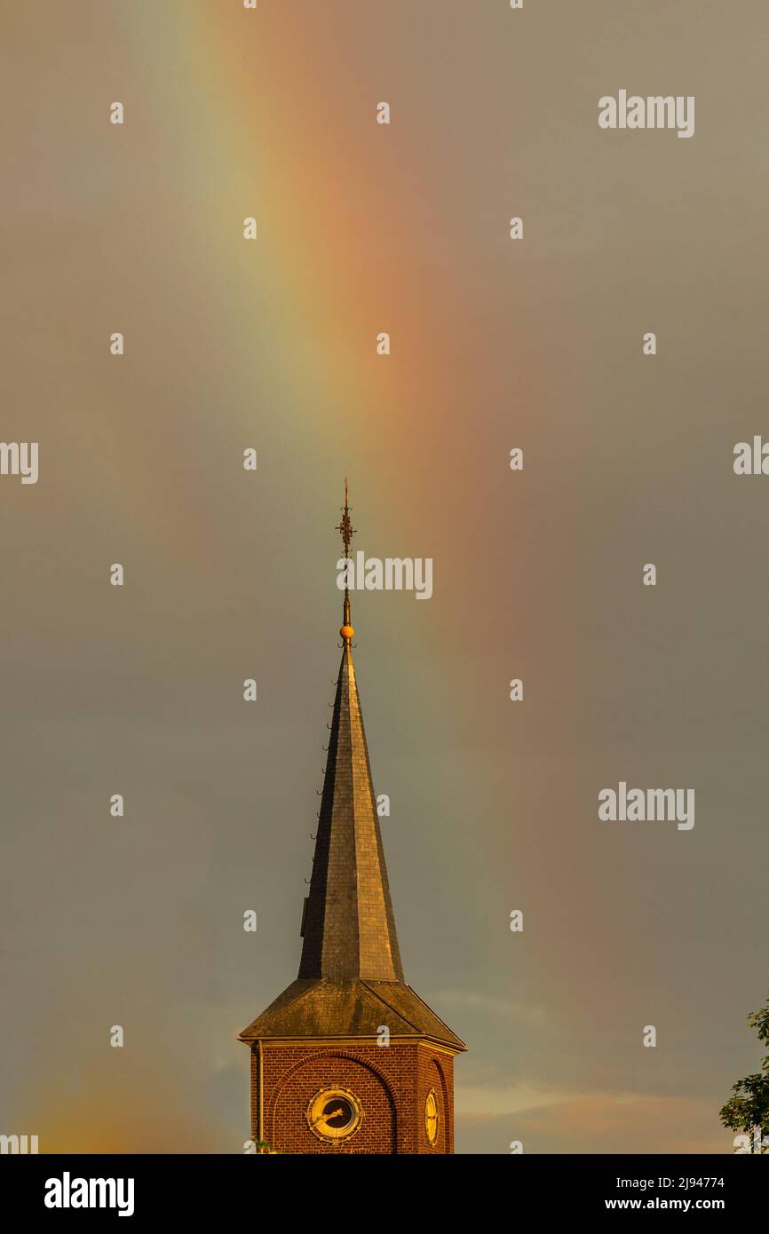 A rainbow touching the religious cross on top of a catholic church ...