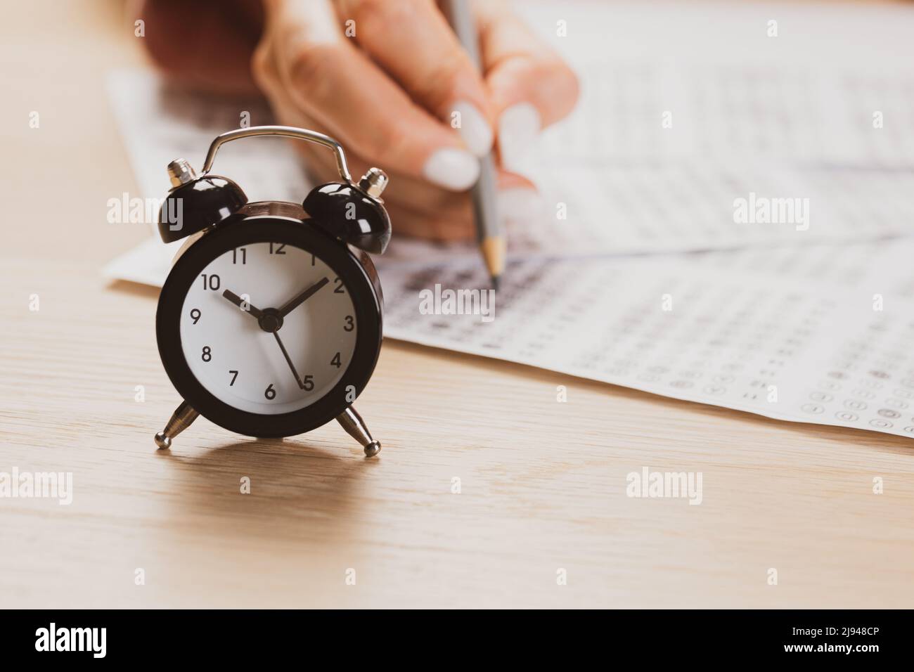 alarm clock with time running out. Students hands to take exams, write ...