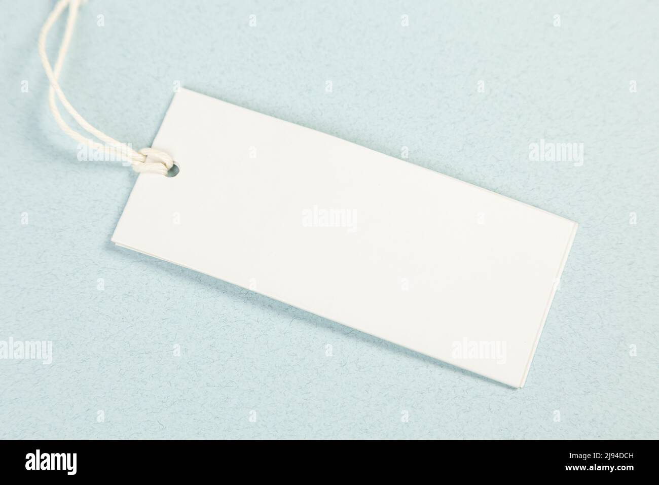 An empty white price tag lies on a gray-blue background with a soft ...