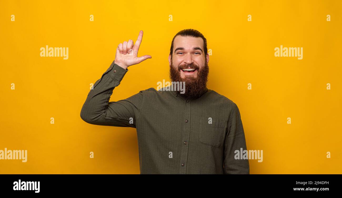 Panorama photo of a bearded man pointing up at the copy space above him ...