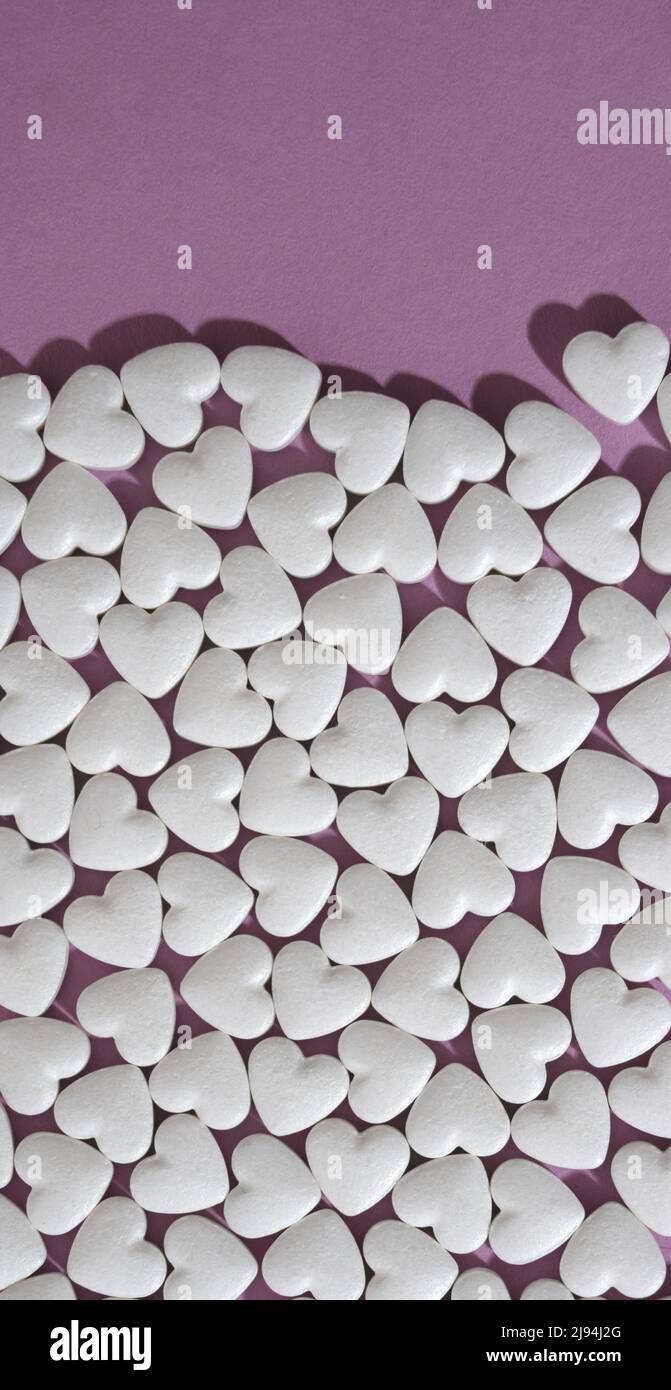 Spilled white heart shape pills on pink background with copy space ...