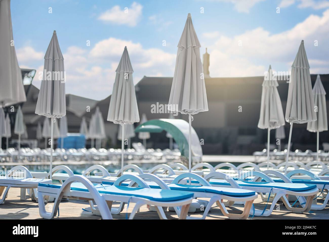 Empty luxury resort with swimming pool, blue loungers and folded ...