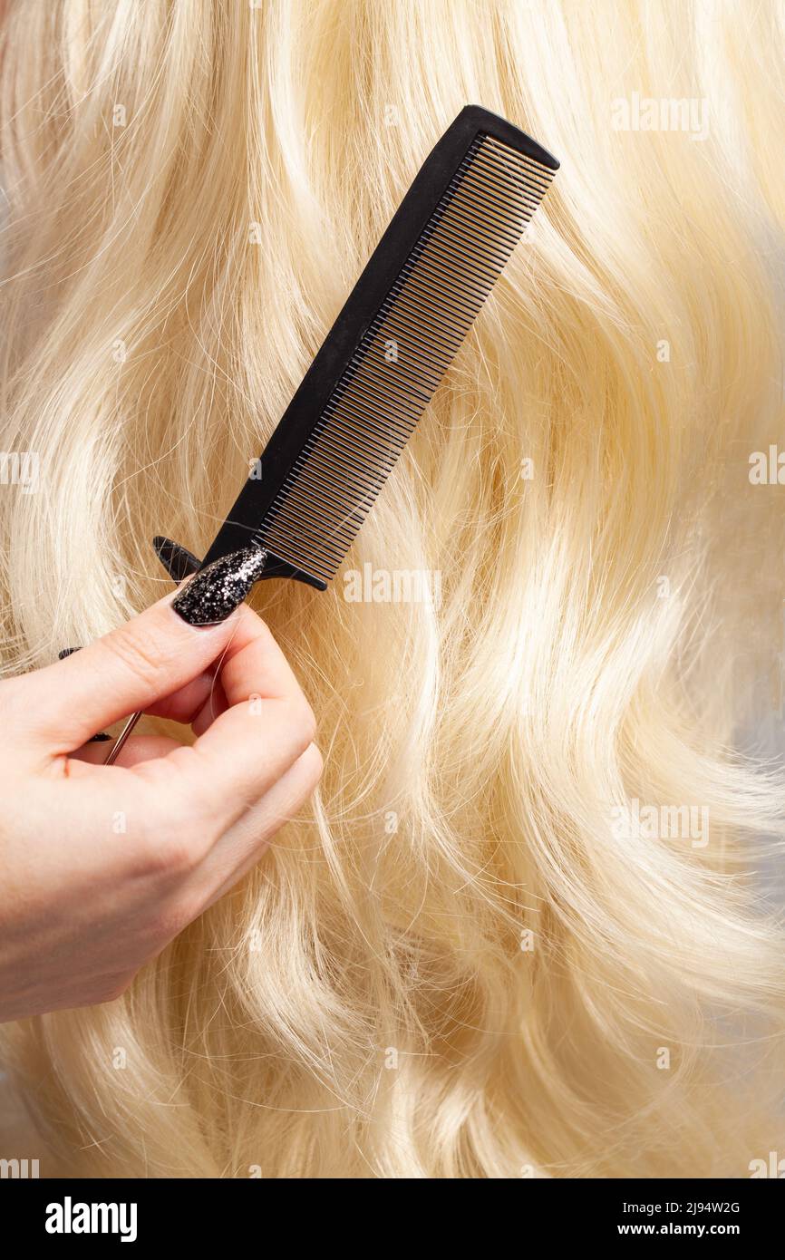 Barber holding comb on long curly blonde hair background closeup Stock ...