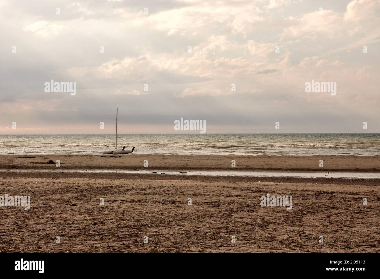 Belgian North Sea beach in De Panne at dawn, with a little sailing boat ...