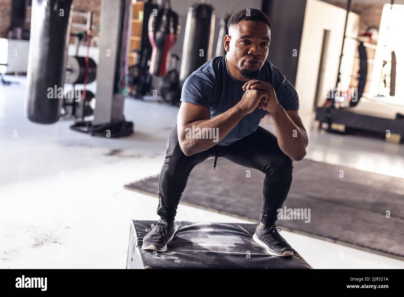 African american young male boxer looking away while squatting on ...