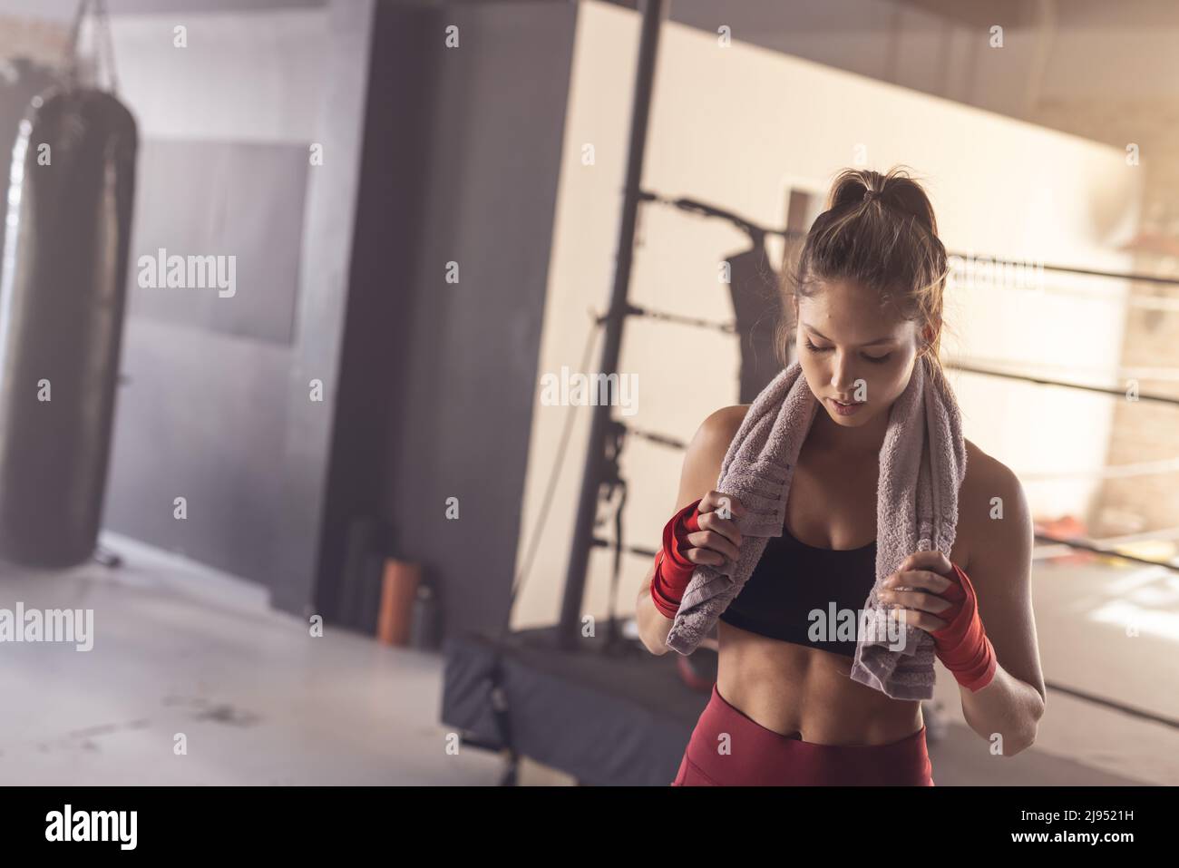 Caucasian young female boxer wearing boxing wraps with towel around ...