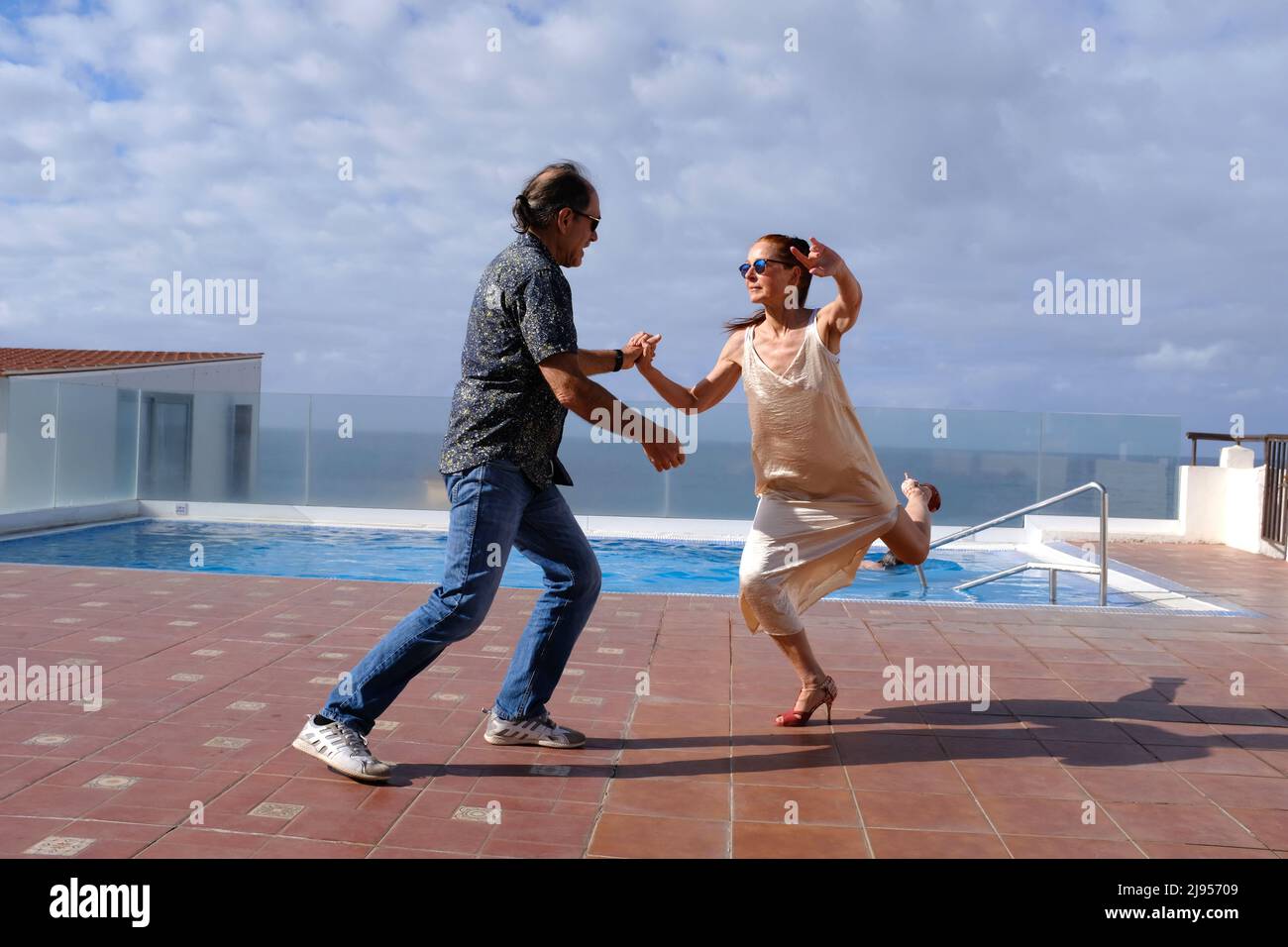 A middle-aged couple practice dancing the tango by a swimming pool ...