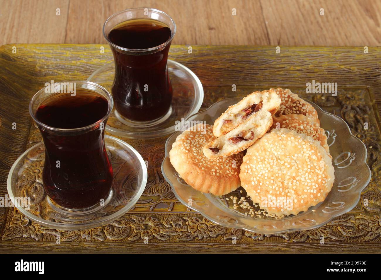 Date filled or stuffed pastry with sesame and two black tea glass in ...