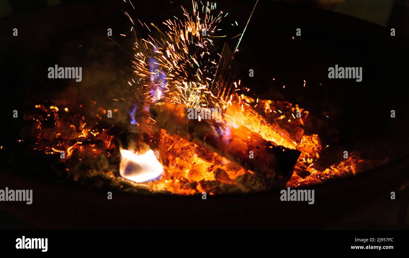 Flying sparks whilst stoking an outdoor fire Stock Photo - Alamy