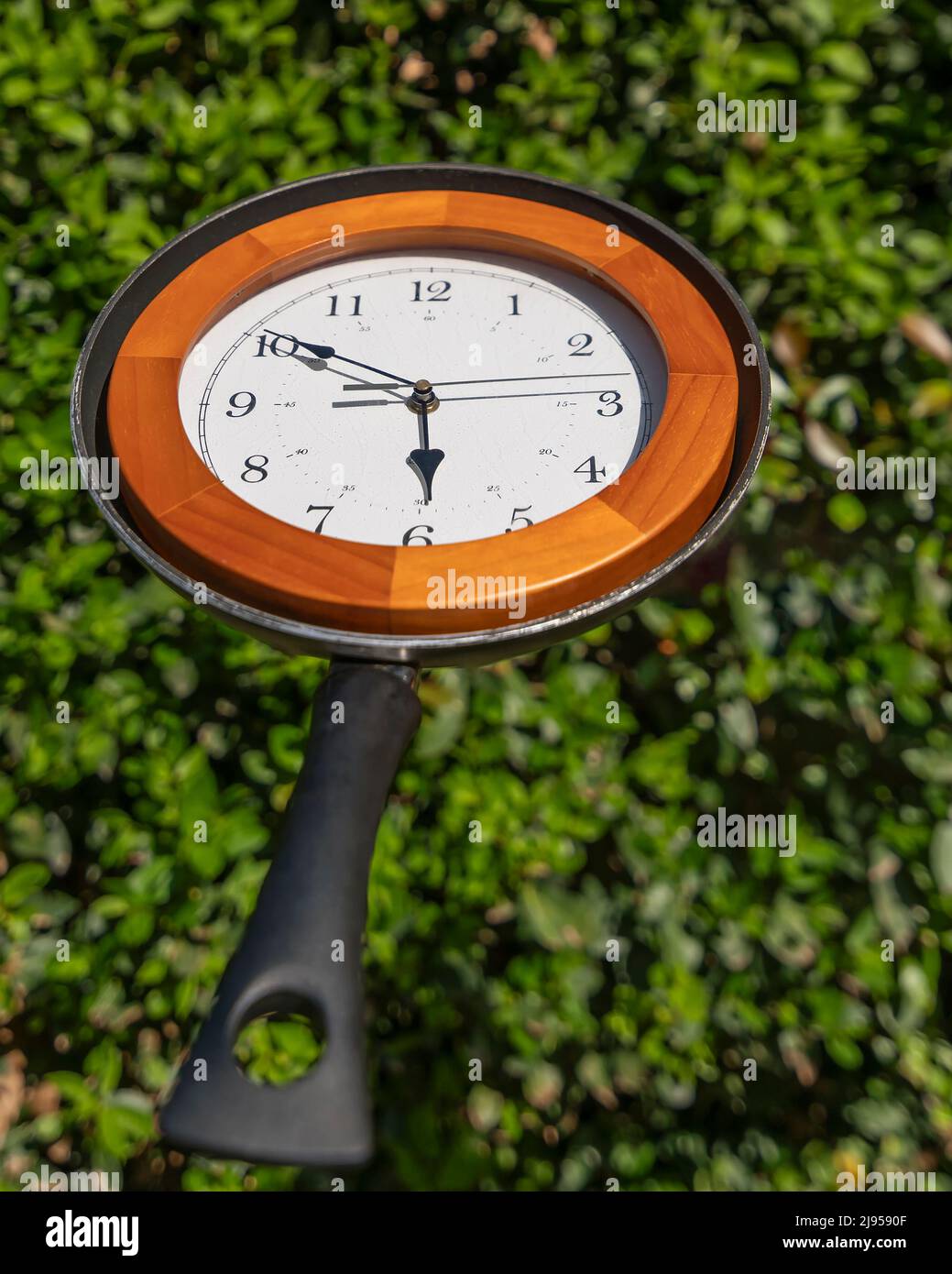 A wall clock is in a pan, against a green background Stock Photo - Alamy