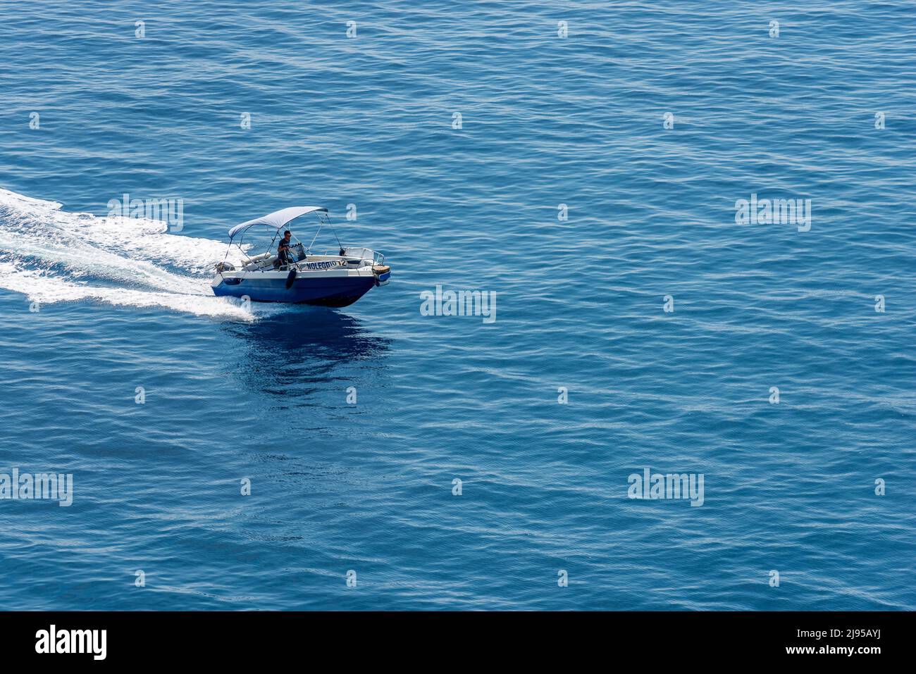 Small blue motor boat with one person on board runs fast in the blue ...