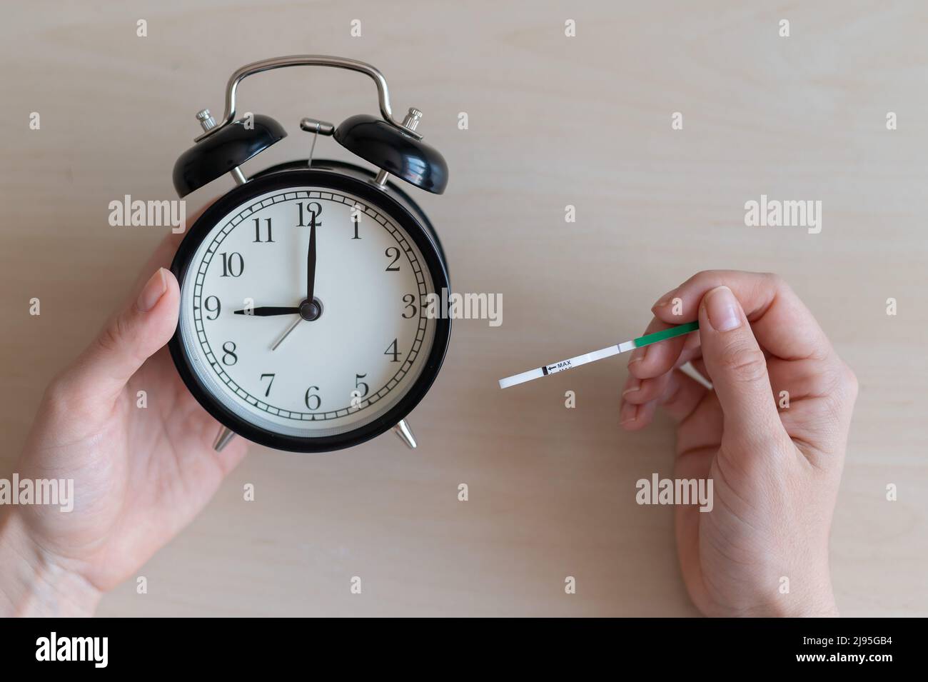 Woman holds negative ovulation test and alarm clock. Female fertility ...