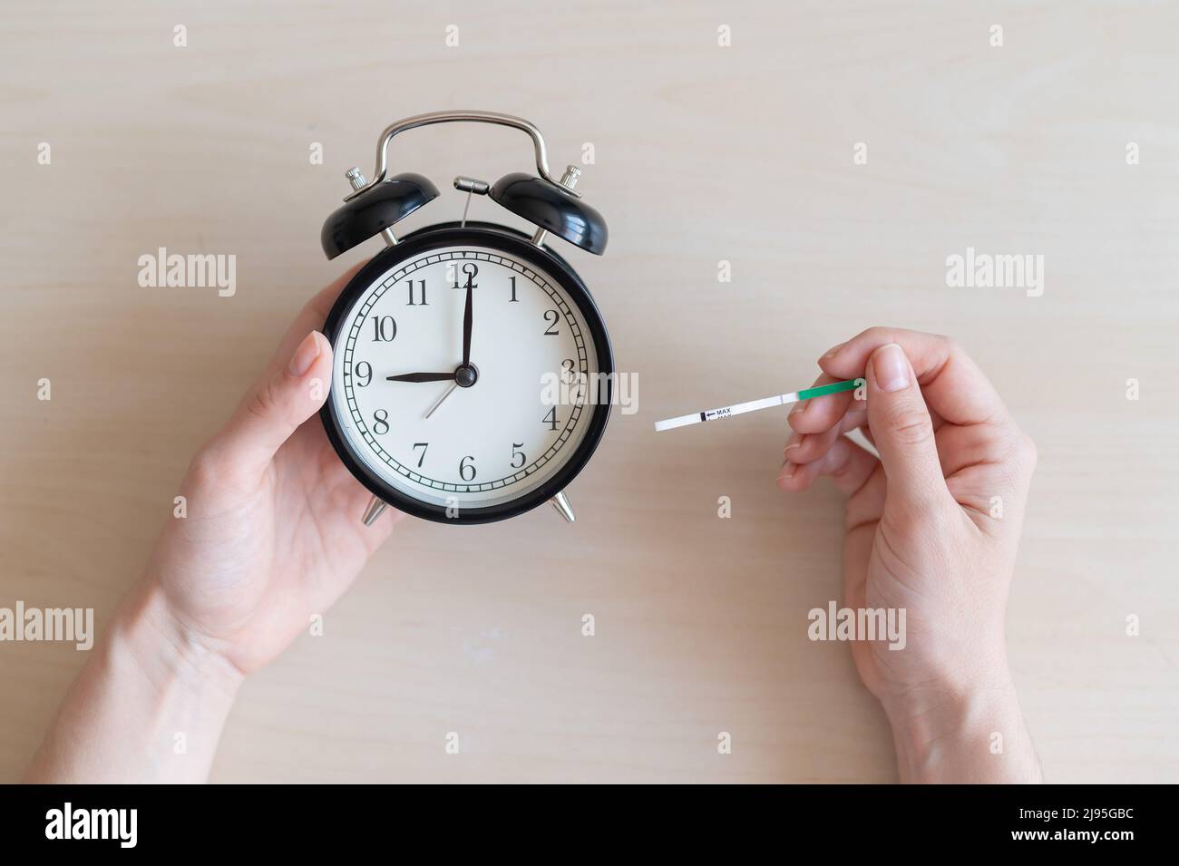 Woman holds negative ovulation test and alarm clock. Female fertility ...