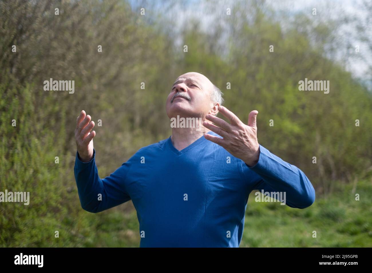 Senior runner with armband doing stretching, breathing fresh air ...