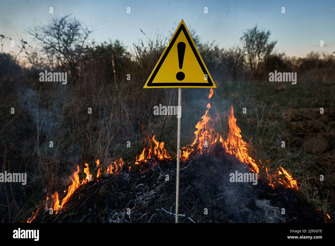 Burning dry grass and warning sign with exclamation mark warns about ...