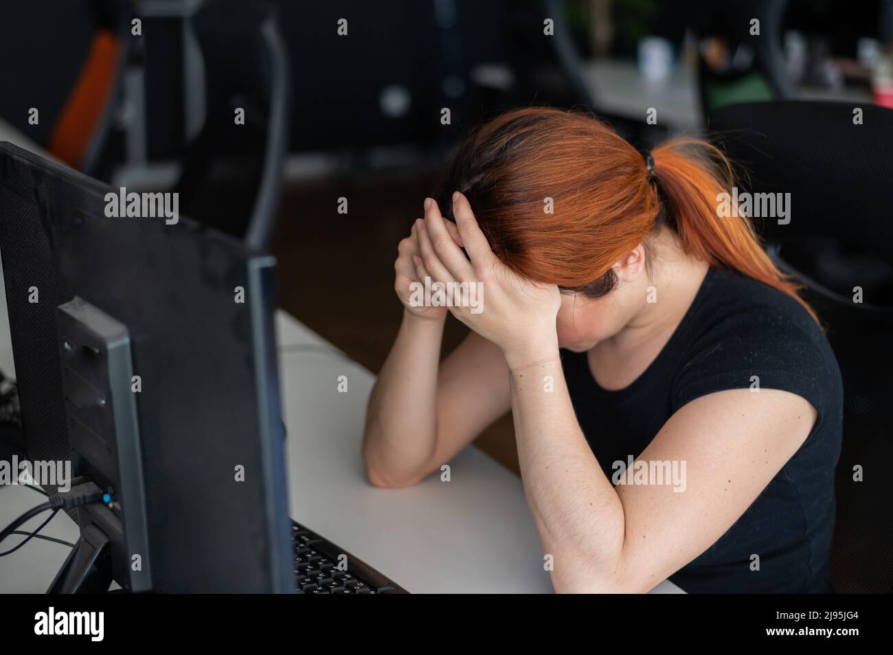 Tired woman workaholic t-shirt in an empty office. Female IT manager in ...