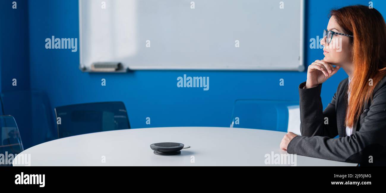 Pensive red-haired office manager in glasses and a suit in an empty ...