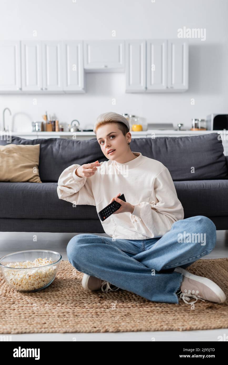 focused woman with tv remote controller eating popcorn and watching ...